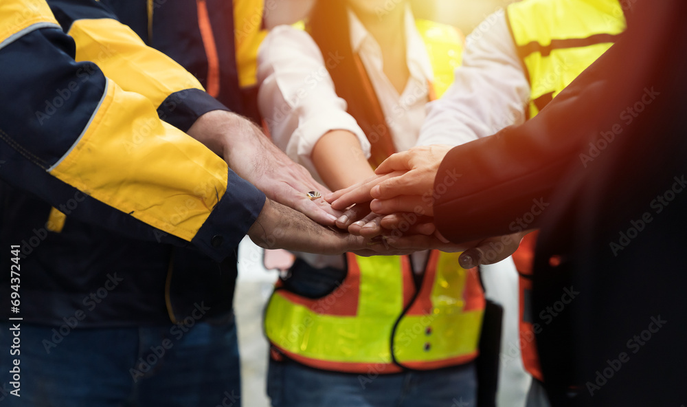 Group of male and female factory workers standing putting their hands ...