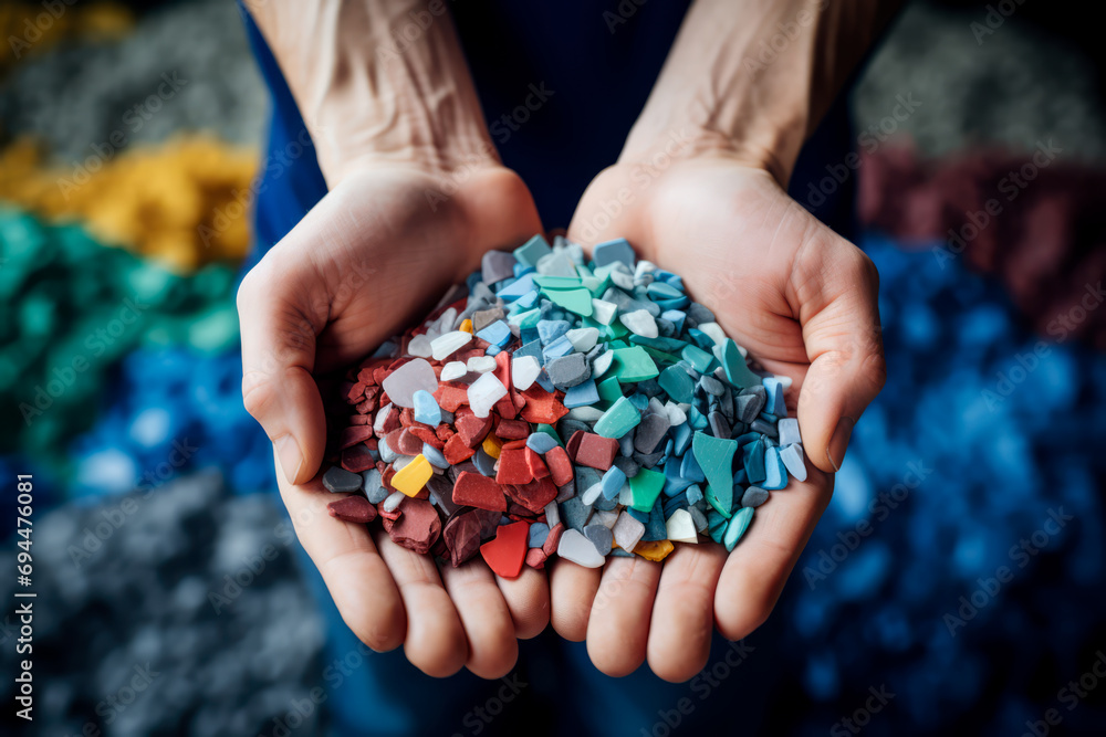 Hand holding small recycled plastic chips as raw material in production ...