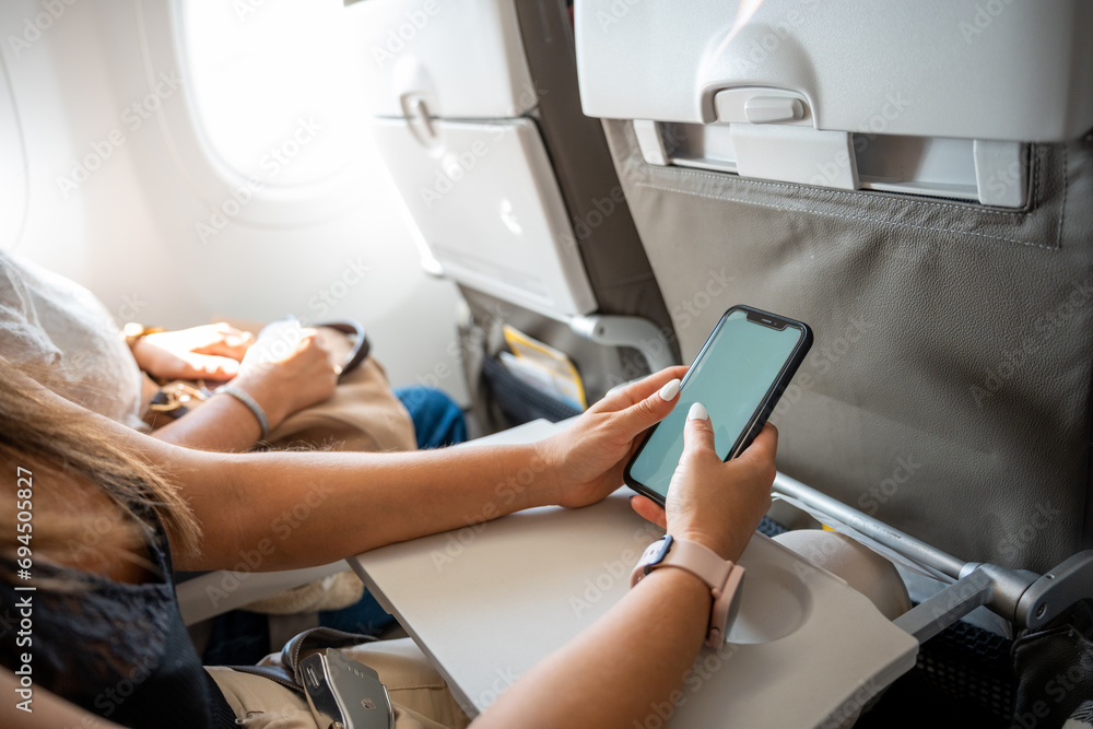 Hands of anonymous woman using her phone while flying in an airplane ...