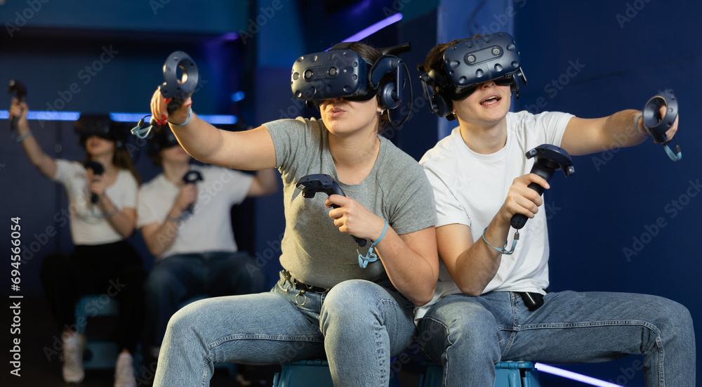 Male and female friend in helmets and with joysticks are sitting ...