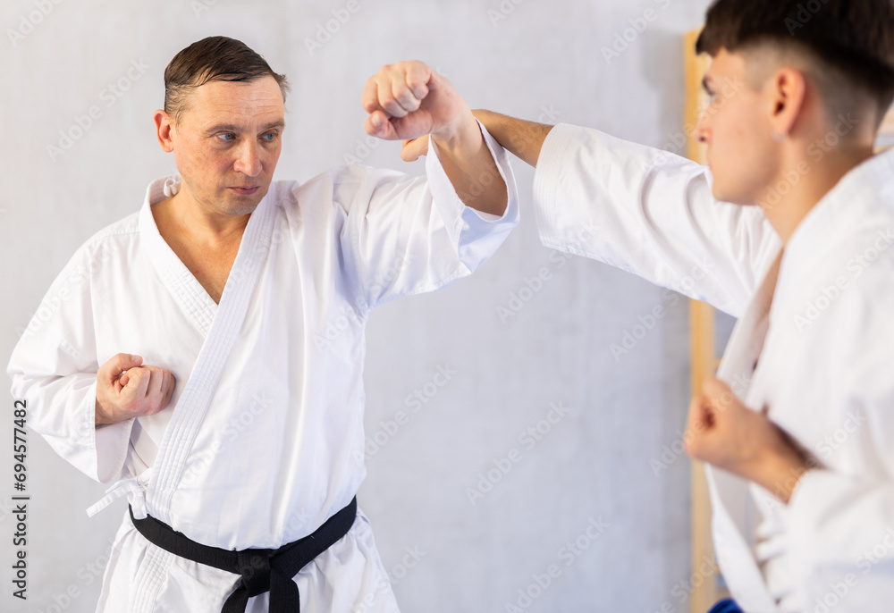 Adult man and young guy karatekas train karate techniques in group in ...