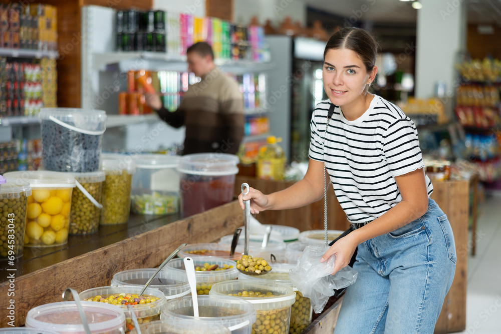 Portrait of interested smiling young female shopper making routine ...