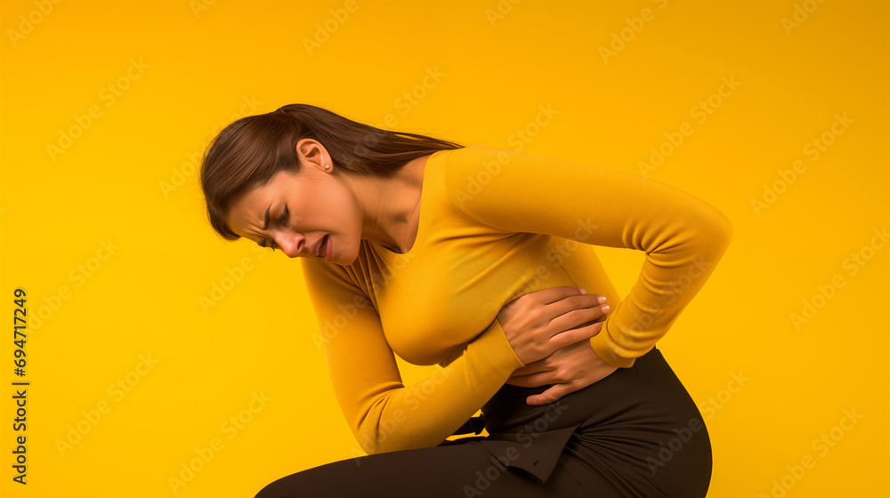 A woman bending over, holding her stomach, with a yellow background ...