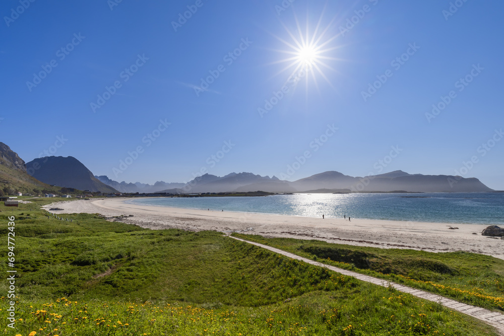 Sunlit pathway meandering through grass and wildflowers to the white ...
