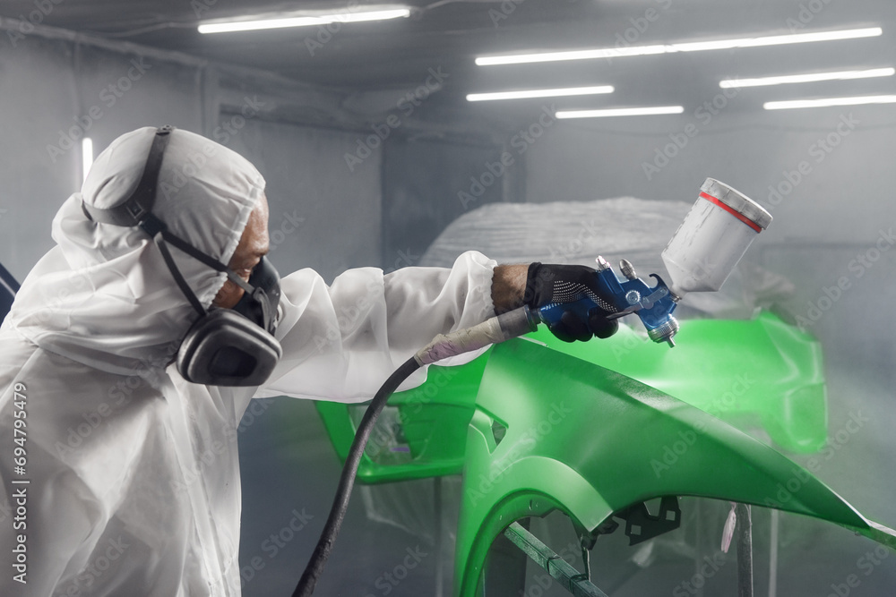 Car paint worker spraying green paint to car body element using spray ...