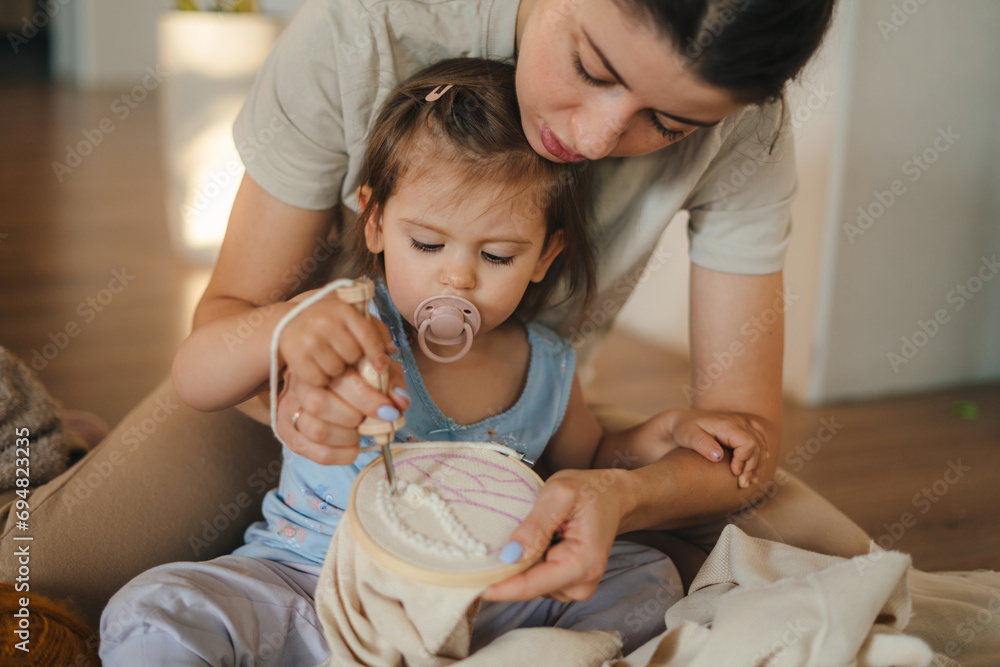 Mom teaching her little daughter to knit. Mom and a little girl sitting ... Mom teaching her little daughter to knit. Mom and a little girl sitting ...