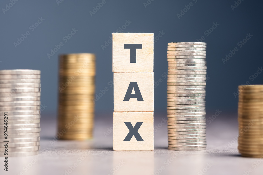 Tax word by wood cubes with different heights of money heaps, tax ...