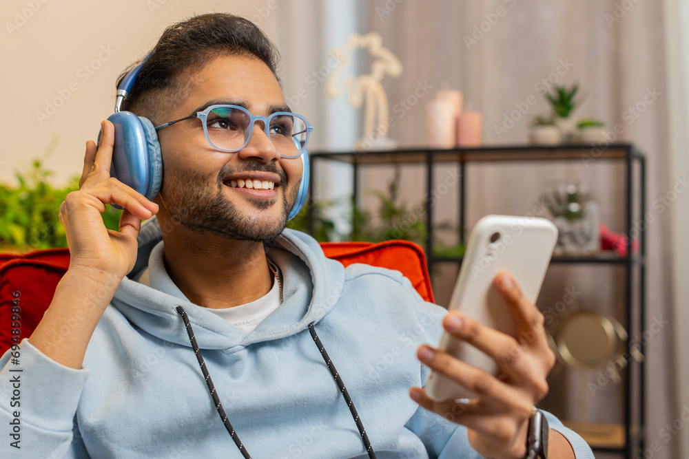 Happy relaxed overjoyed Indian Hindu man in wireless headphones dancing ...