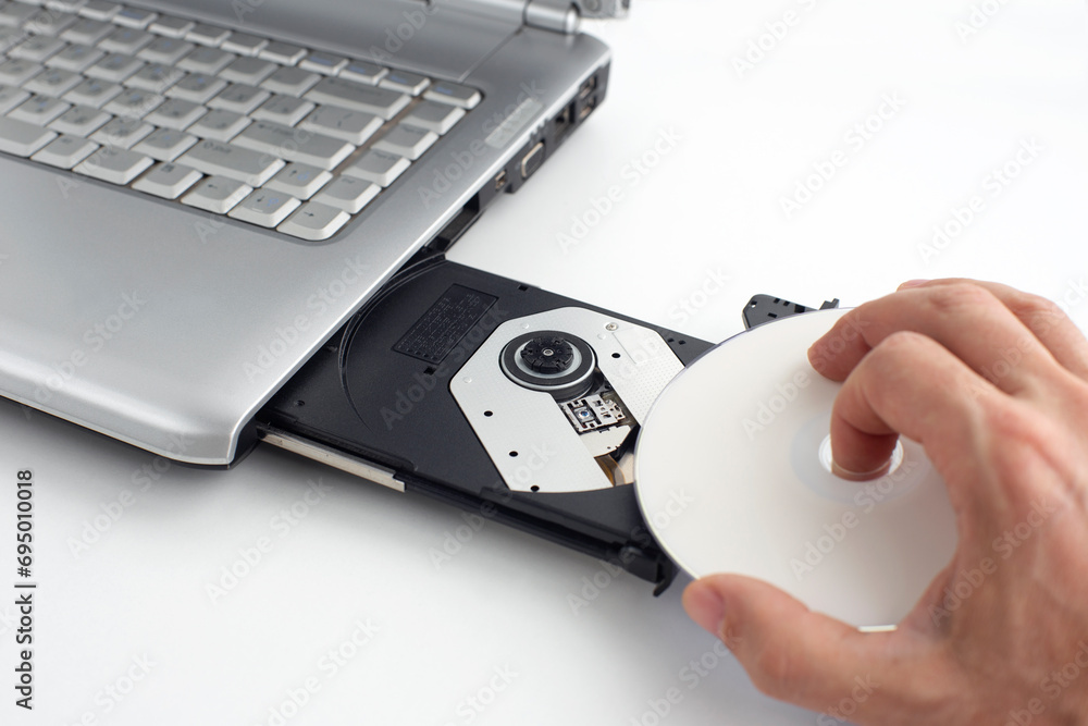 hand inserts dvd disc into laptop, concept of burning data to dvd on ...