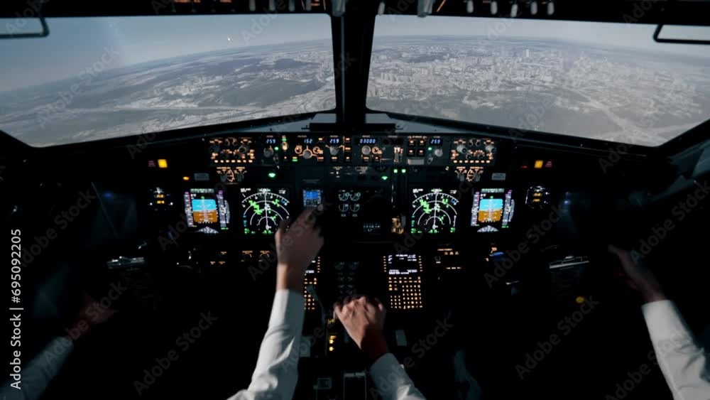 rear view of pilots in the cockpit of an airplane during flight control ...
