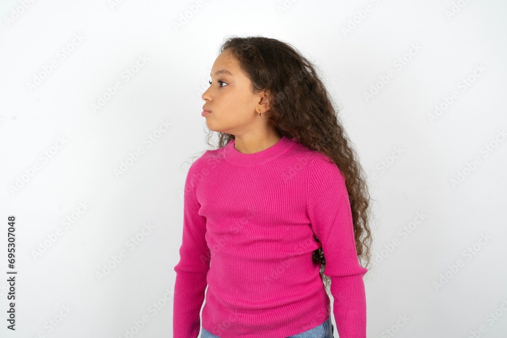 Beautiful kid girl standing over white background stares aside with ...