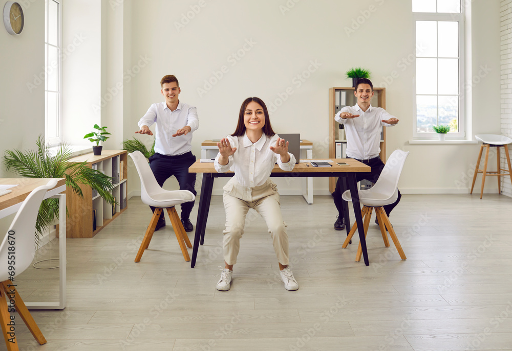 Full length portrait of young business people doing stretching sit-ups ...