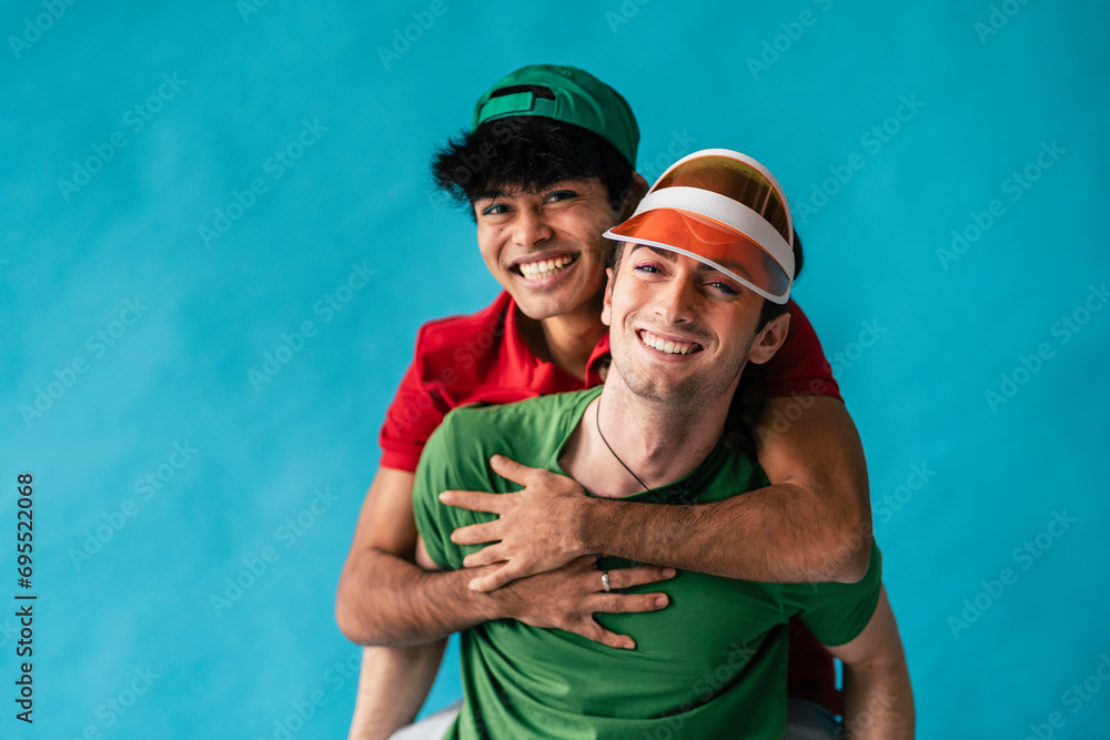 Two men in colorful sportswear share a playful piggyback moment against ...