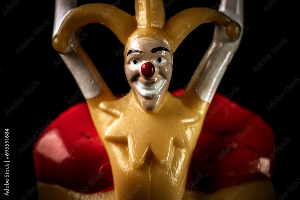 Creepy dirty toy jester in the dark. Scary face of a jester with a red ...