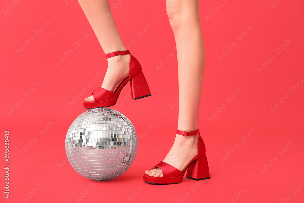 Female legs in trendy high heels with disco ball on red background ...