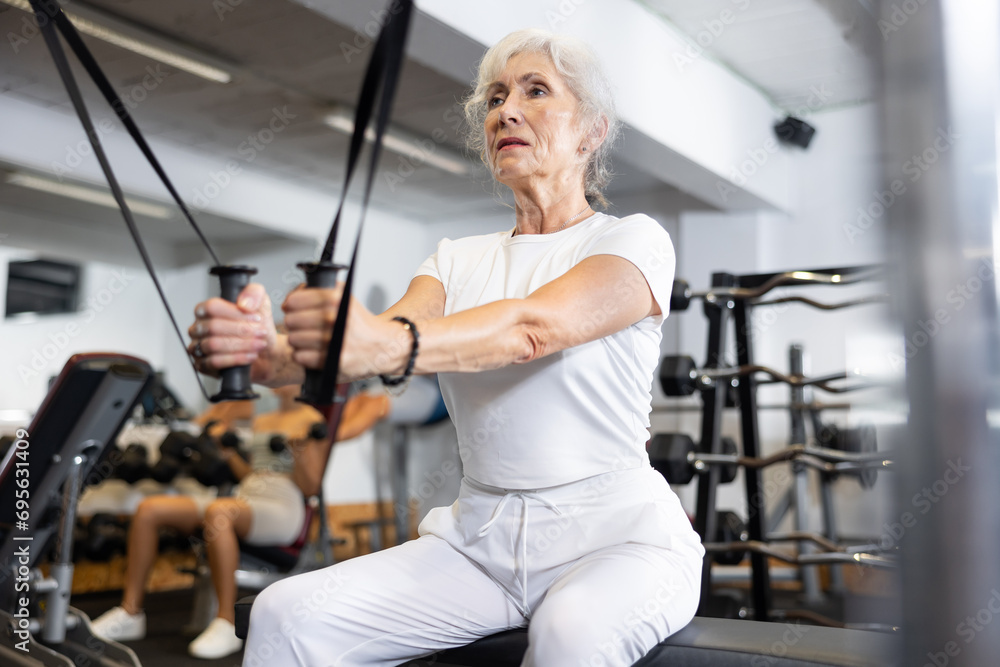 Active athlete mature woman during exercises on crossover exercise ...