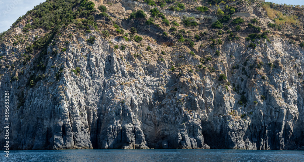 Weathered seaside rock face texture with parts of green and blue water ...