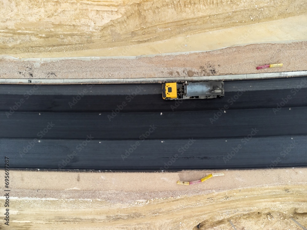 yellow truck pouring bitumen over a new road. Aerial drone shot. Road ...