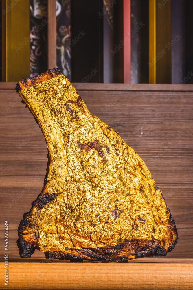Bistecca di carne cotta alla brace e decorata con fogli d'oro edibili ...