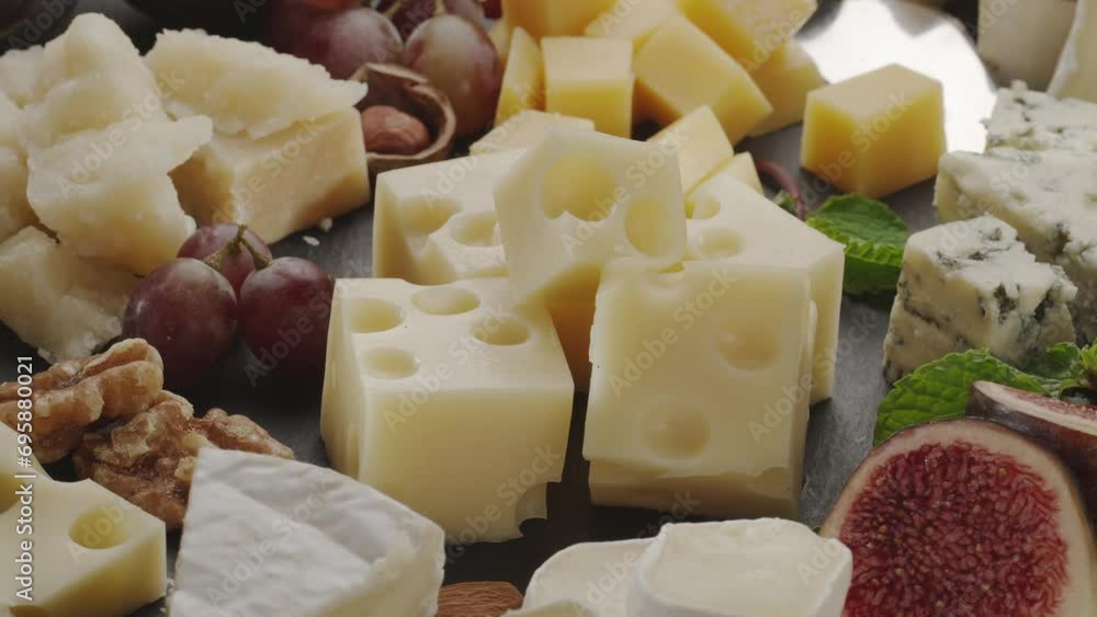 Vidéo Stock Variety of sliced cheeses with fruits, mint, nuts and ...