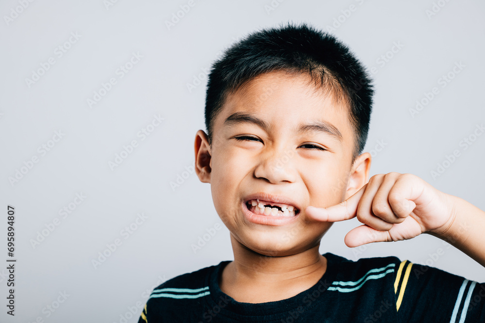 Child an Asian boy highlights dental care by pointing to missing front ...