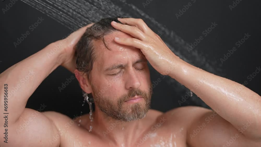 Muscular man washing hair in bath. Guy bathing shower head in bathtub. Face in foam in shower ...