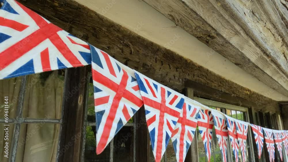 CLOSE UP: String of Union Jack flags strewn under wooden beams of an ...