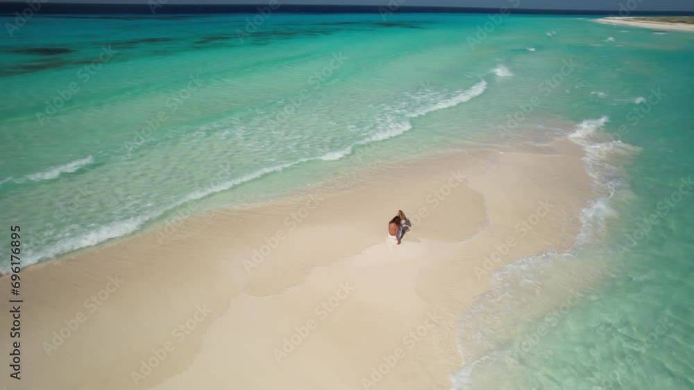 Stunning aerial view woman in white walk and lying on sandbar, waves ...