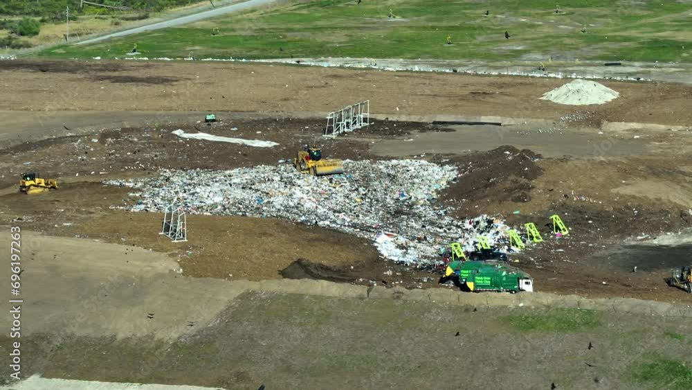 Garbage landfill site with bulldozer tractors burying large amount of ...
