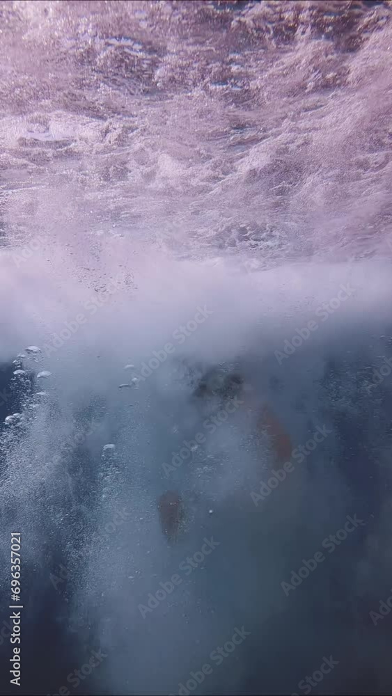 Vertical video, Young men jumping into deep blue sea water, underwater ...