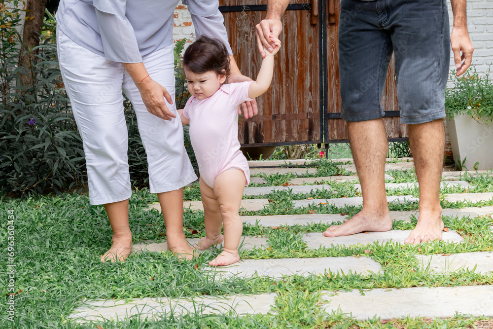 Asian toddler practicing walking in backyard with parents. Father ...