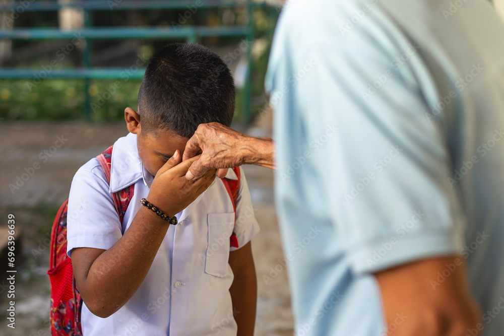 A young school boy pays respect to his grandfather by doing the mano po ...