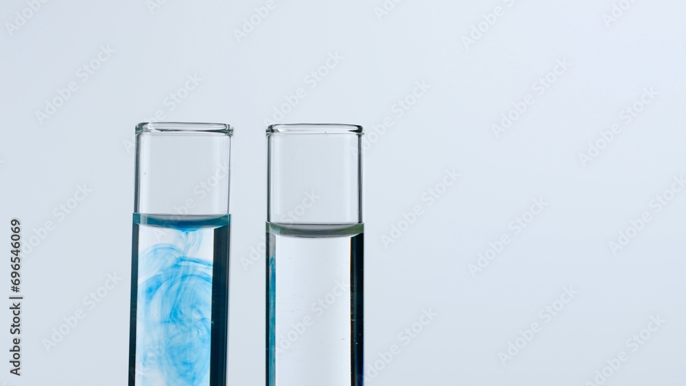 Two glass test tubes on a white background. The test tubes are filled ...