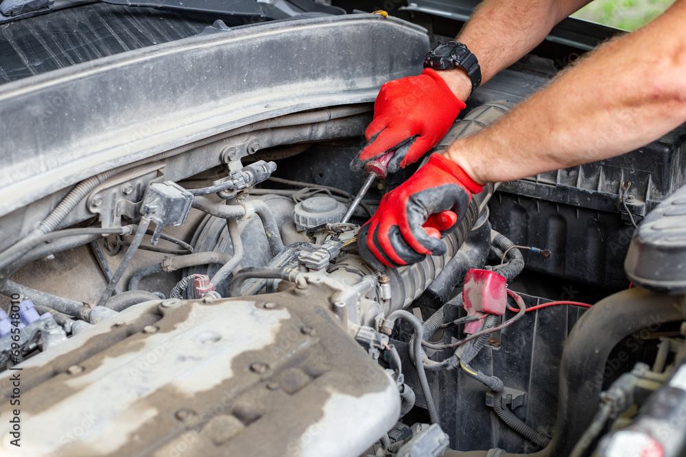 Car repair. The car mechanic unscrews the fasteners to remove the air ...