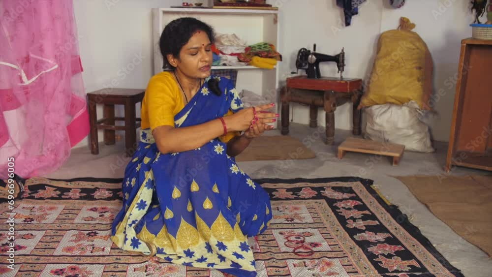 An attractive Indian woman in a traditional dress is putting on bangles ...