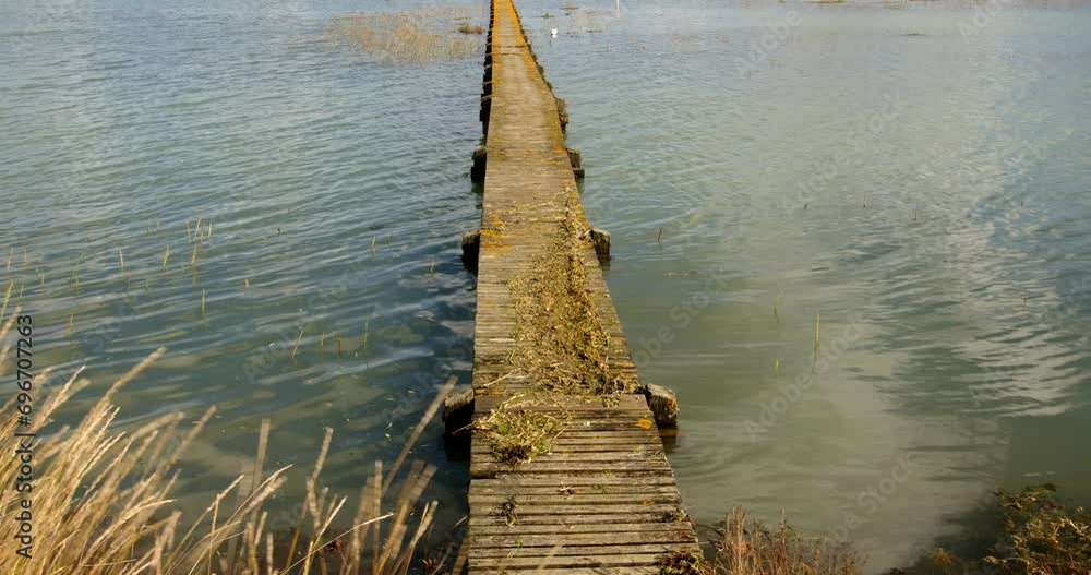 wide mid shot of a long wooden jetty with flooding debris on top. Taken ...