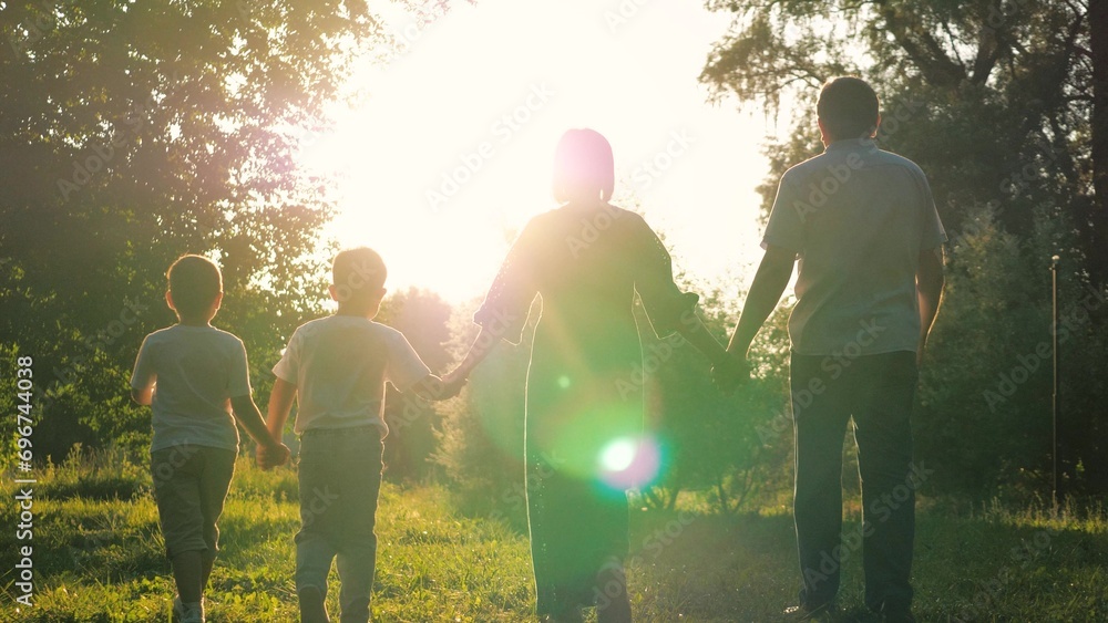 Happy children and joyful parents walk joining hands across meadow on ...