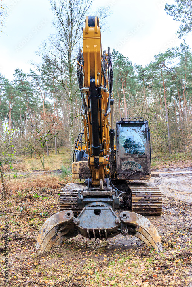 Front view of an excavator grapple, bare trees in the background ...