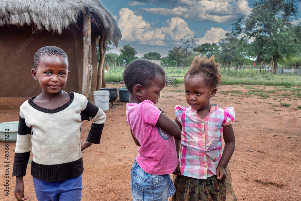 village african kids, playing in the yard , three siblings, hut with ...