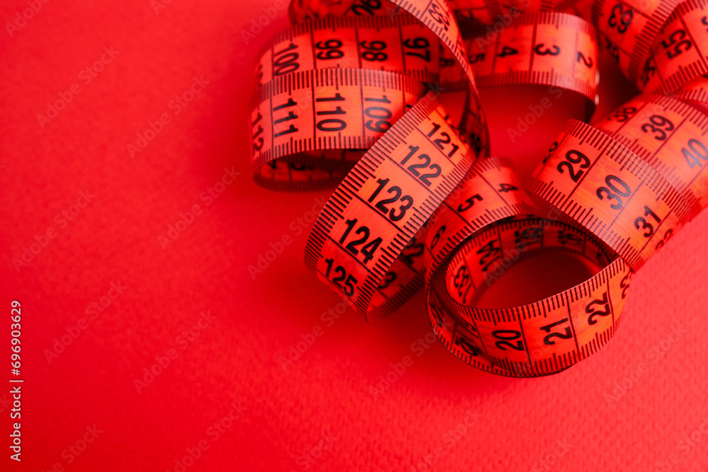 Red measuring tape on a red background. Tool for measuring length and ...