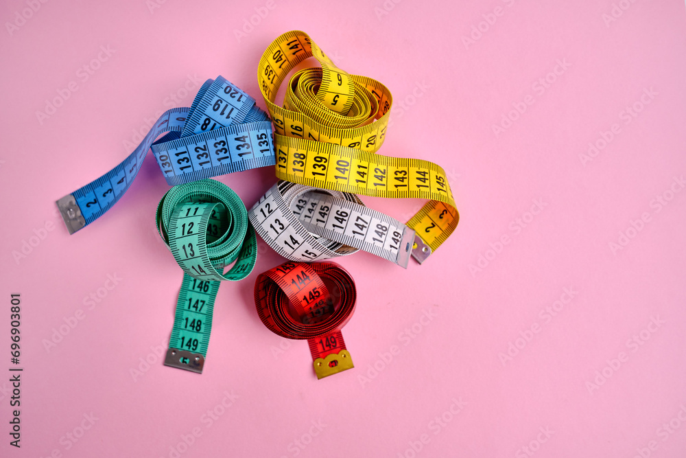 Multi-colored measuring tapes on a light background. Tool for measuring ...