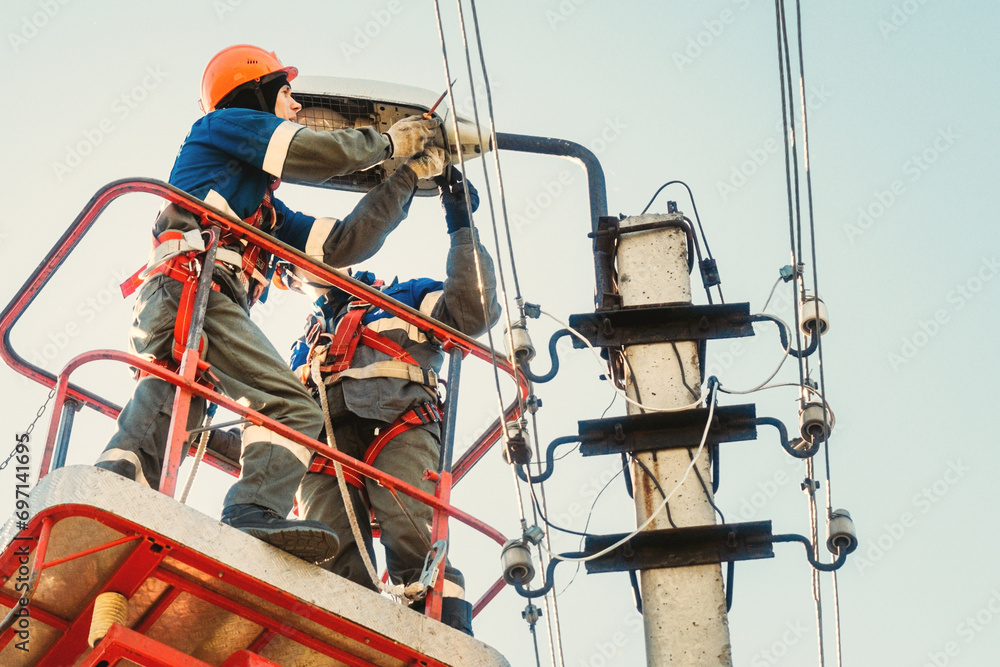 Two electricians from cradle of aerial platform or crane are repairing ...
