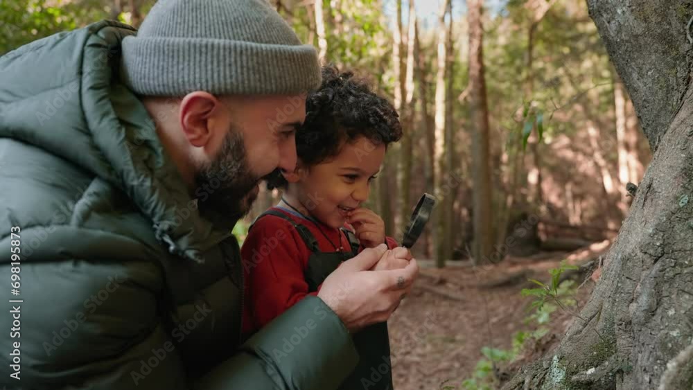 Warm scene of a father in a jacket and hat exploring the forest with ...