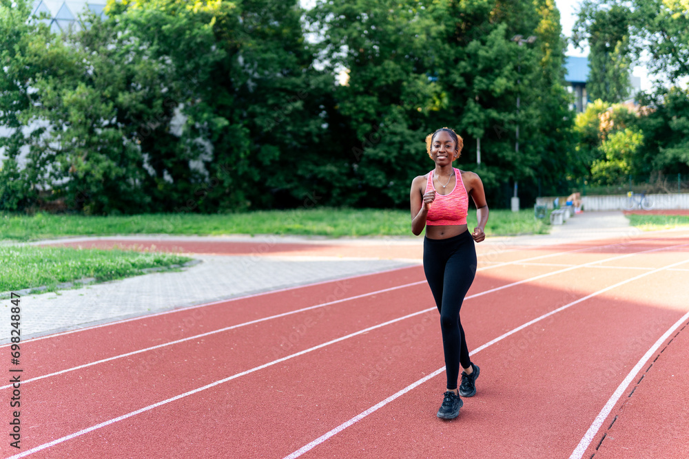 Foto de The confident black woman casually jogs on a running track ...