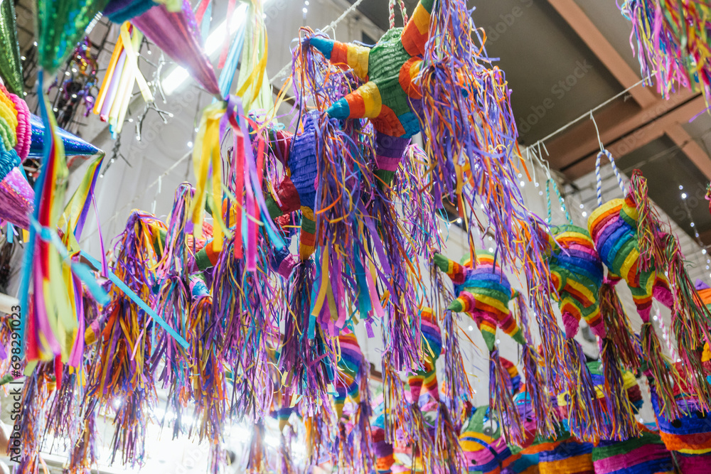 Colorful piñatas of different shapes and sizes hanging over the stalls ...