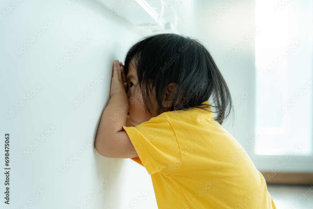 little asian children kid playing hide and seek standing next wall ...