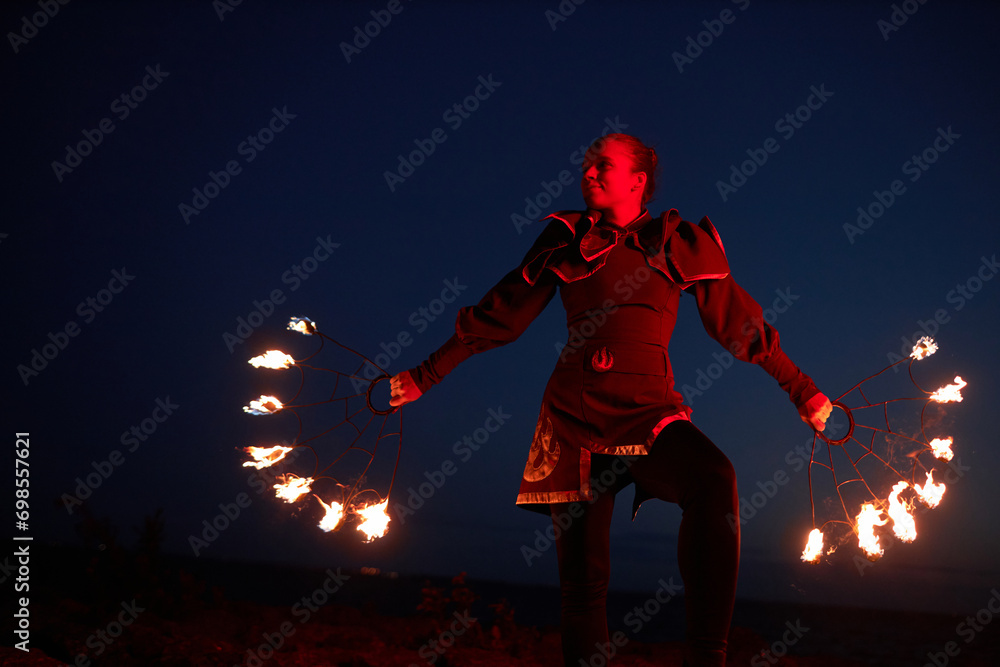 Full length portrait of performer dancing with fire fans outdoors at ...