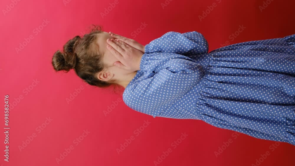 Vertical video of shocked little girl covers face with hands, posing ...