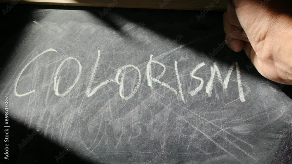 Hand writing the word racism, discrimination, apartheid, colourism ...