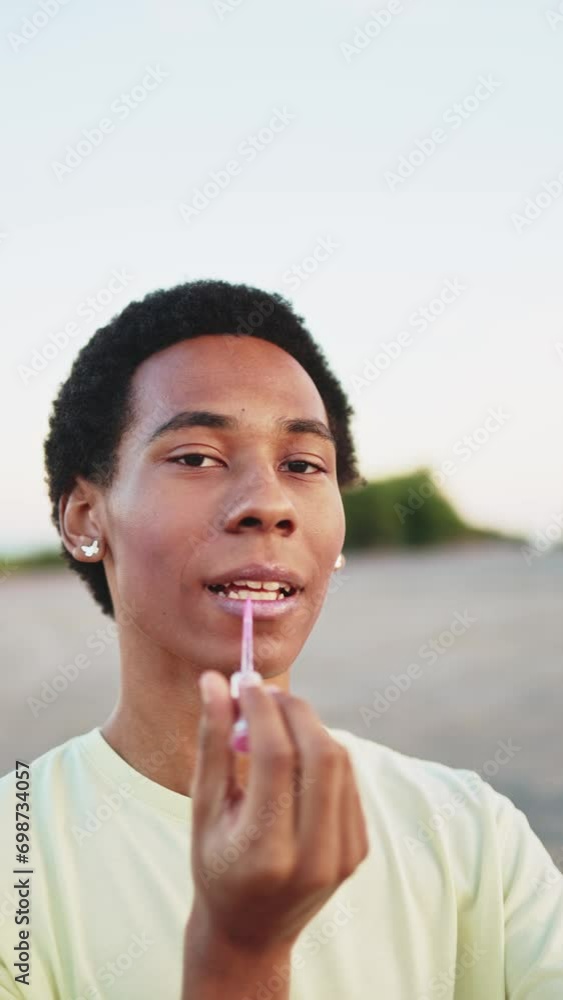 Vertical video of a beautiful young non-binary person putting on make ...